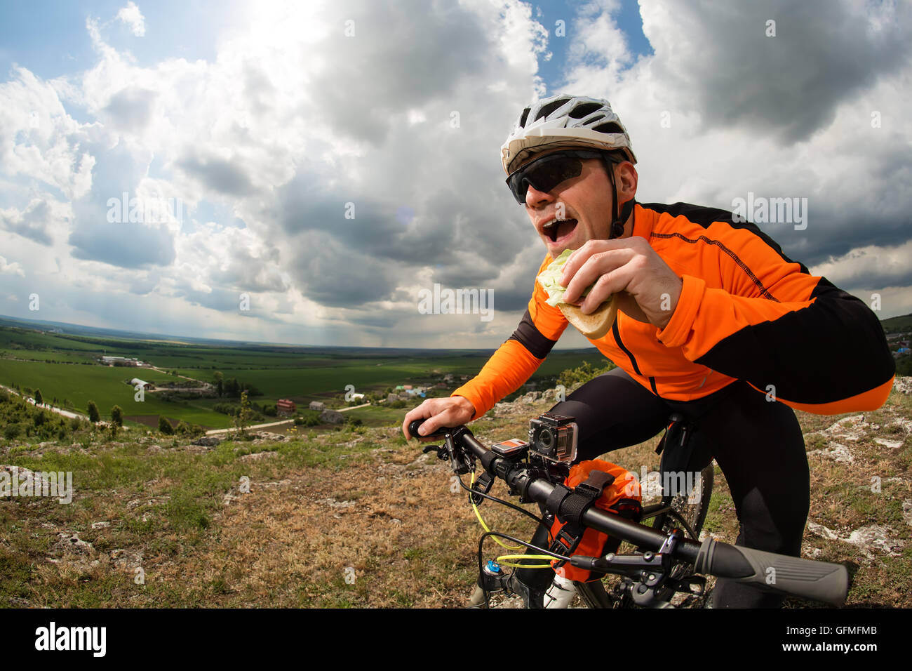 Active man sitting on bike and eating sandwich Stock Photo - Alamy