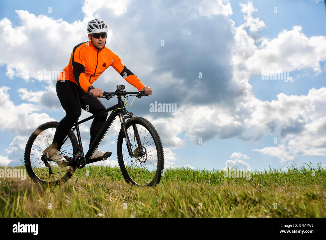 Young man cycling on a rural road through green meadow Stock Photo - Alamy
