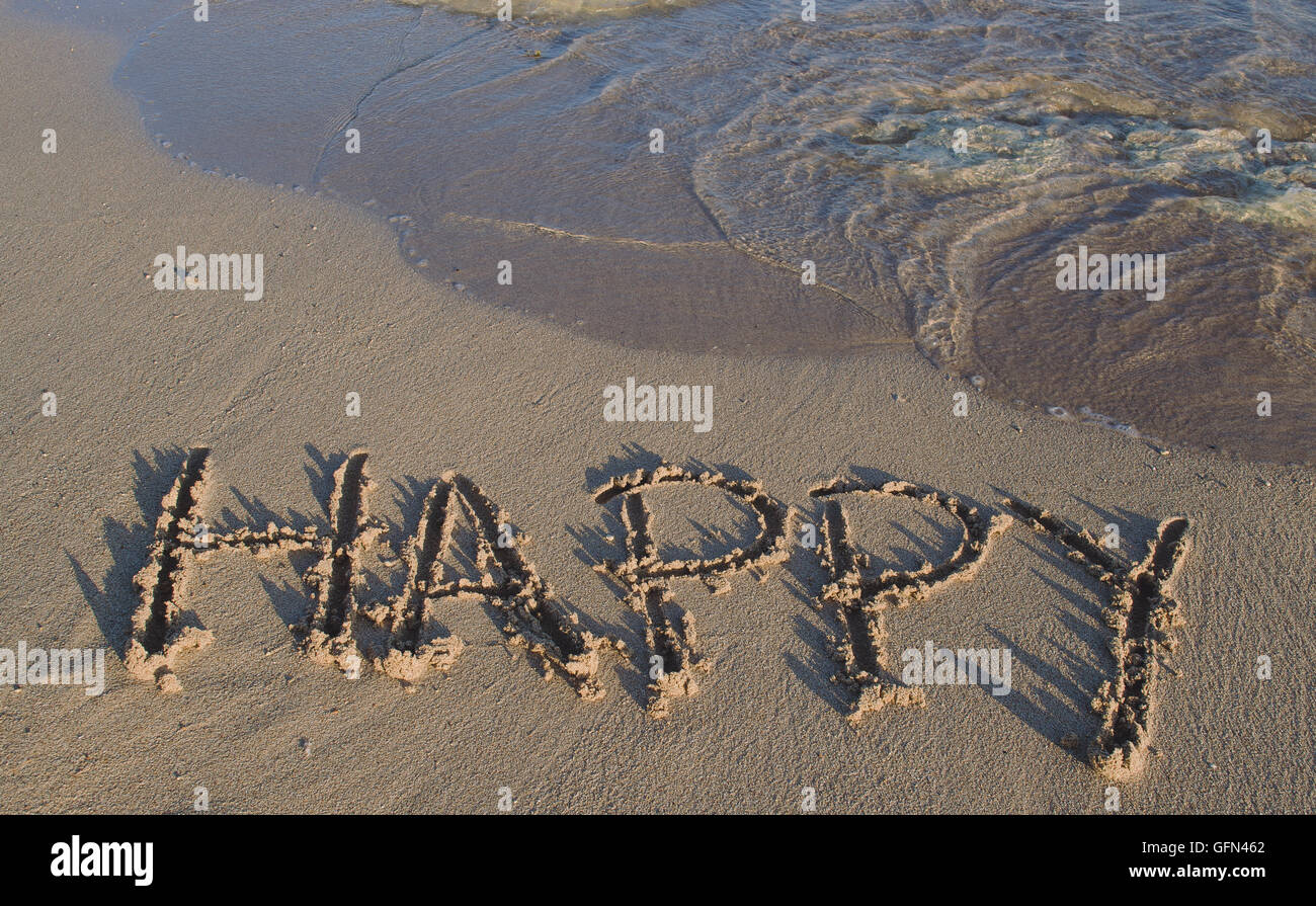Happy - drawn on sea beach sand Stock Photo - Alamy