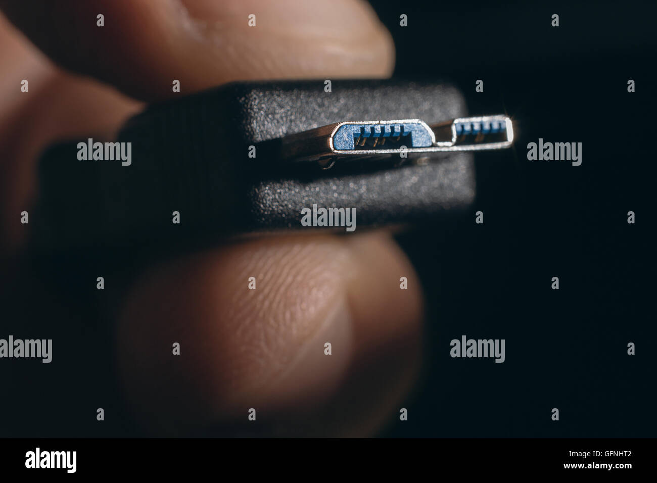 Hand holding black micro USB 3.0 cable. Man's hand holds a USB ...
