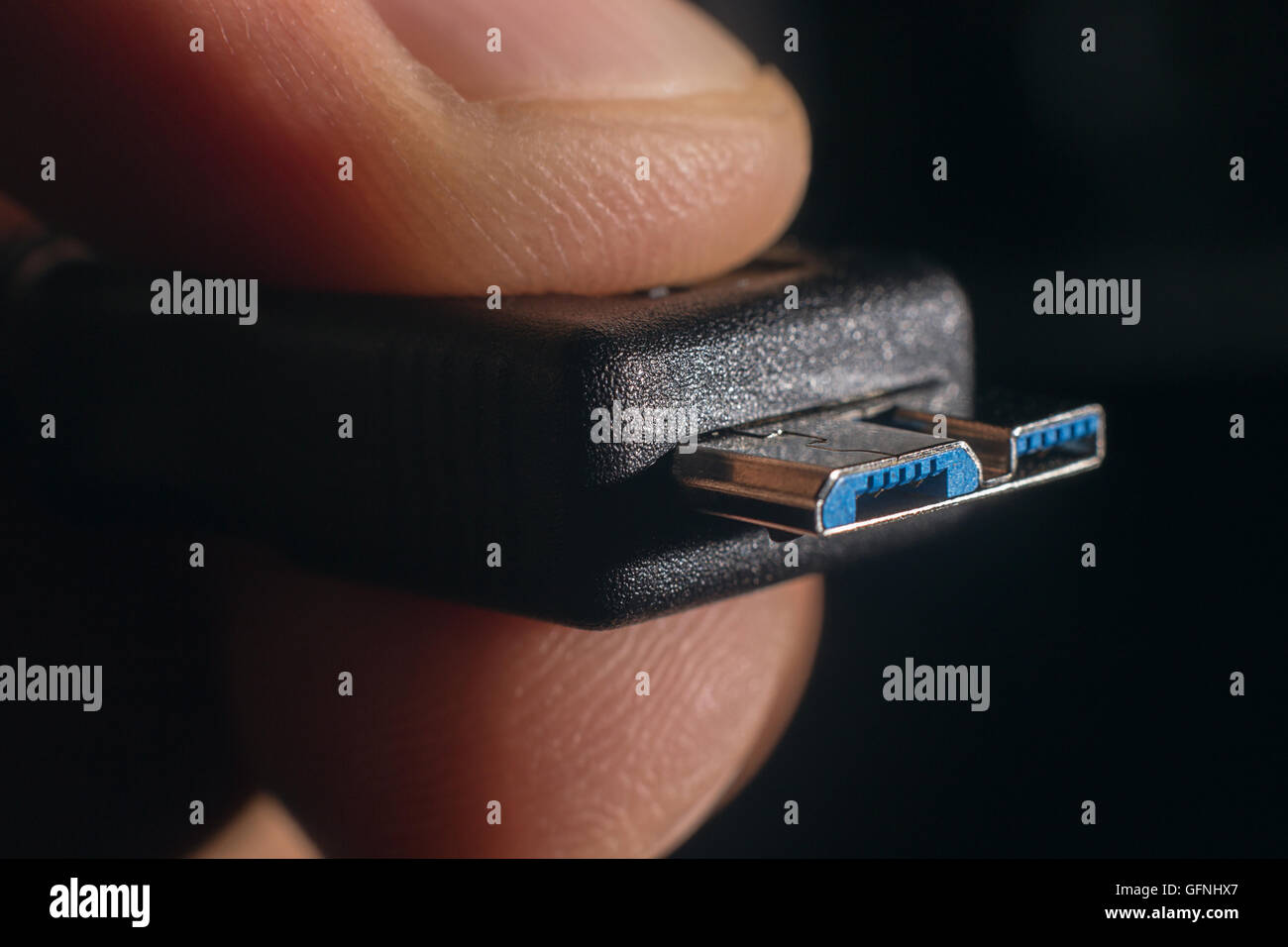 Hand holding black micro USB 3.0 cable. Man's hand holds a USB ...