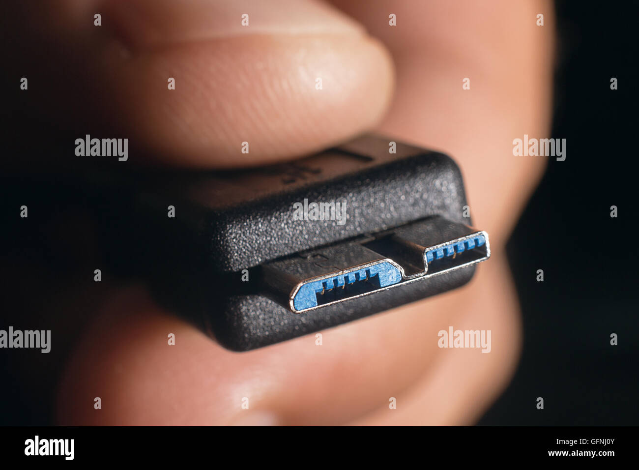 Hand holding black micro USB 3.0 cable. Man's hand holds a USB ...