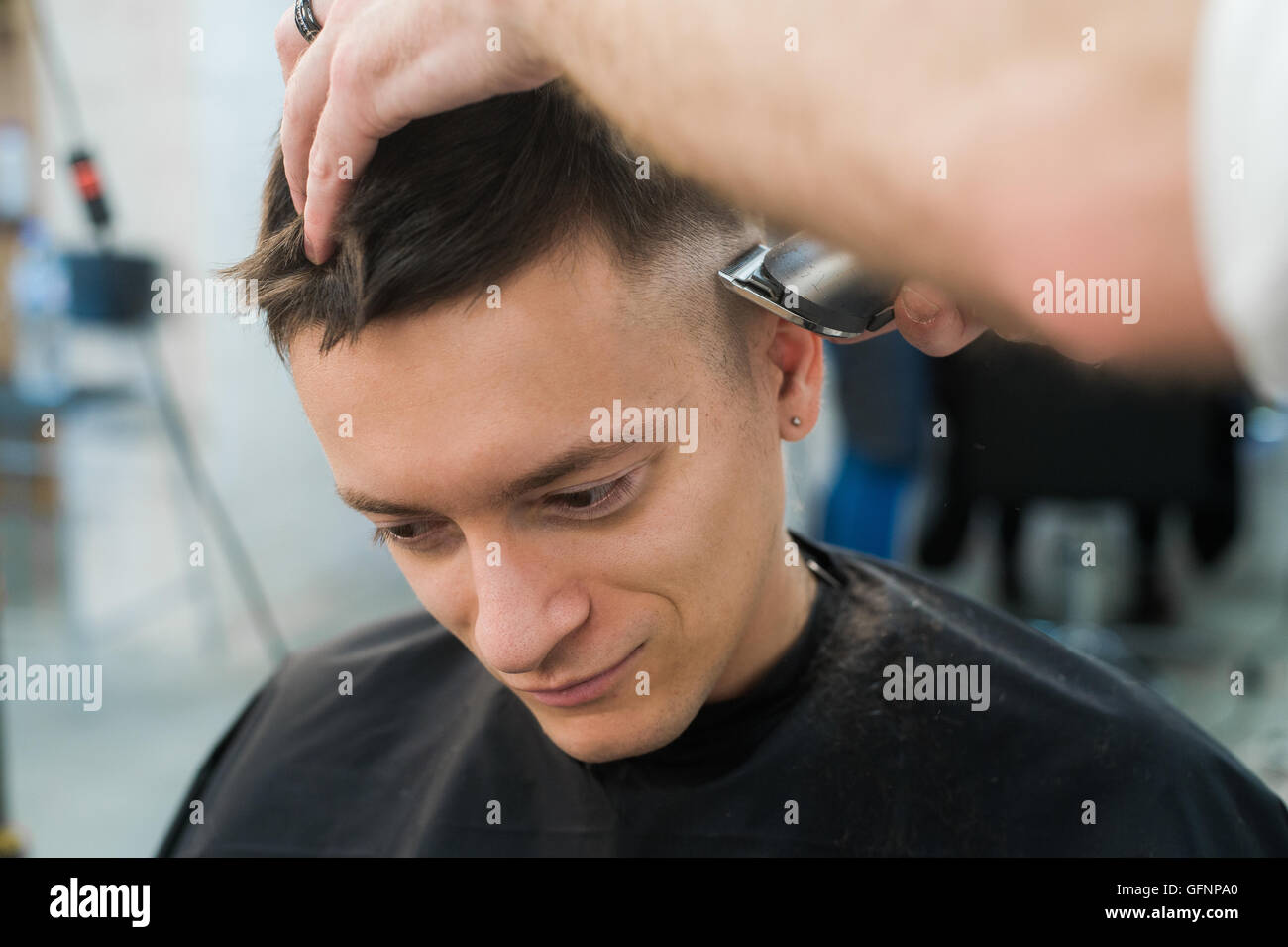Professional styling. Close up side view of young man getting haircut ...
