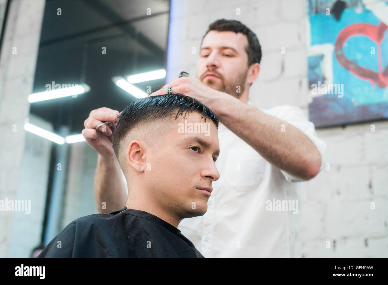 Professional styling. Close up side view of young man getting haircut ...