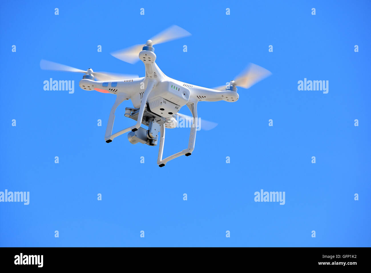 White drone with video camera hovering in bright blue sky Stock Photo ...