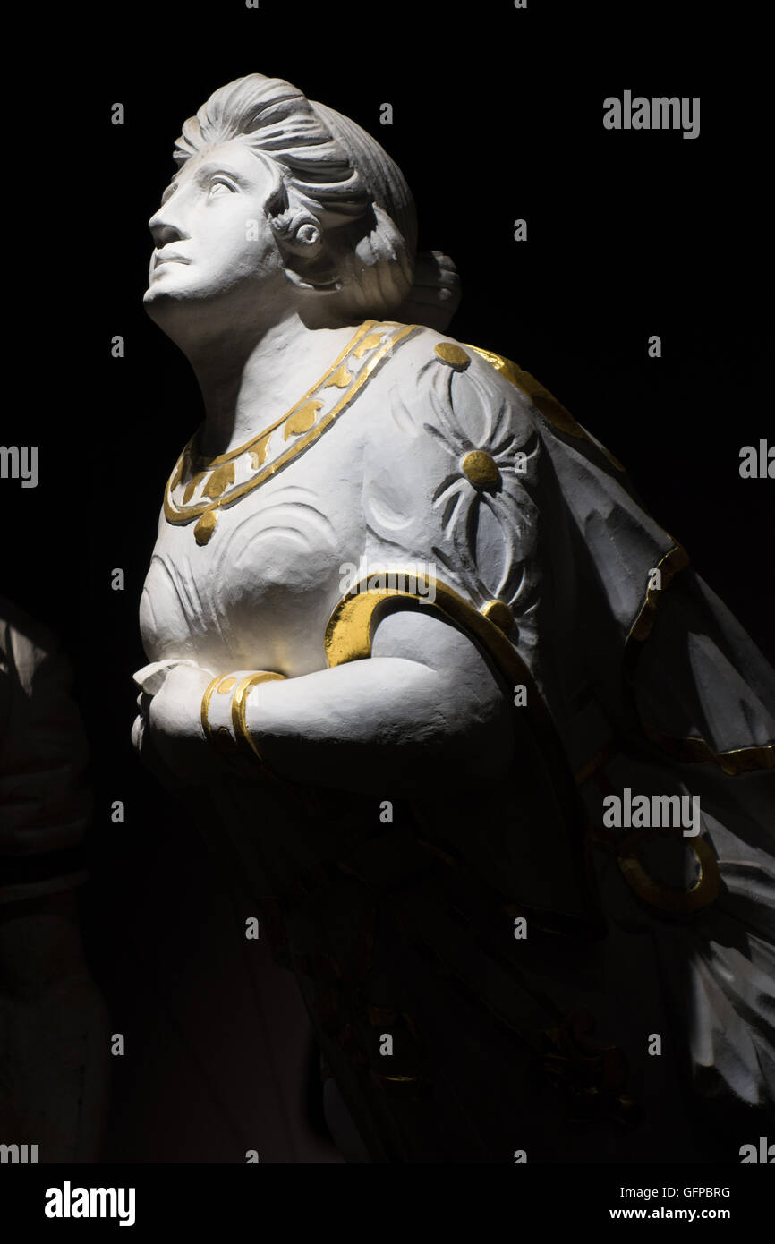 A carved wooden female ship's figurehead is mounted on the wall at the ...