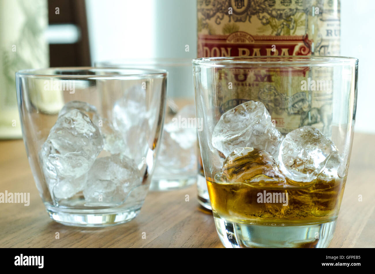 A bottle of rum an sum glasses with ice Stock Photo - Alamy