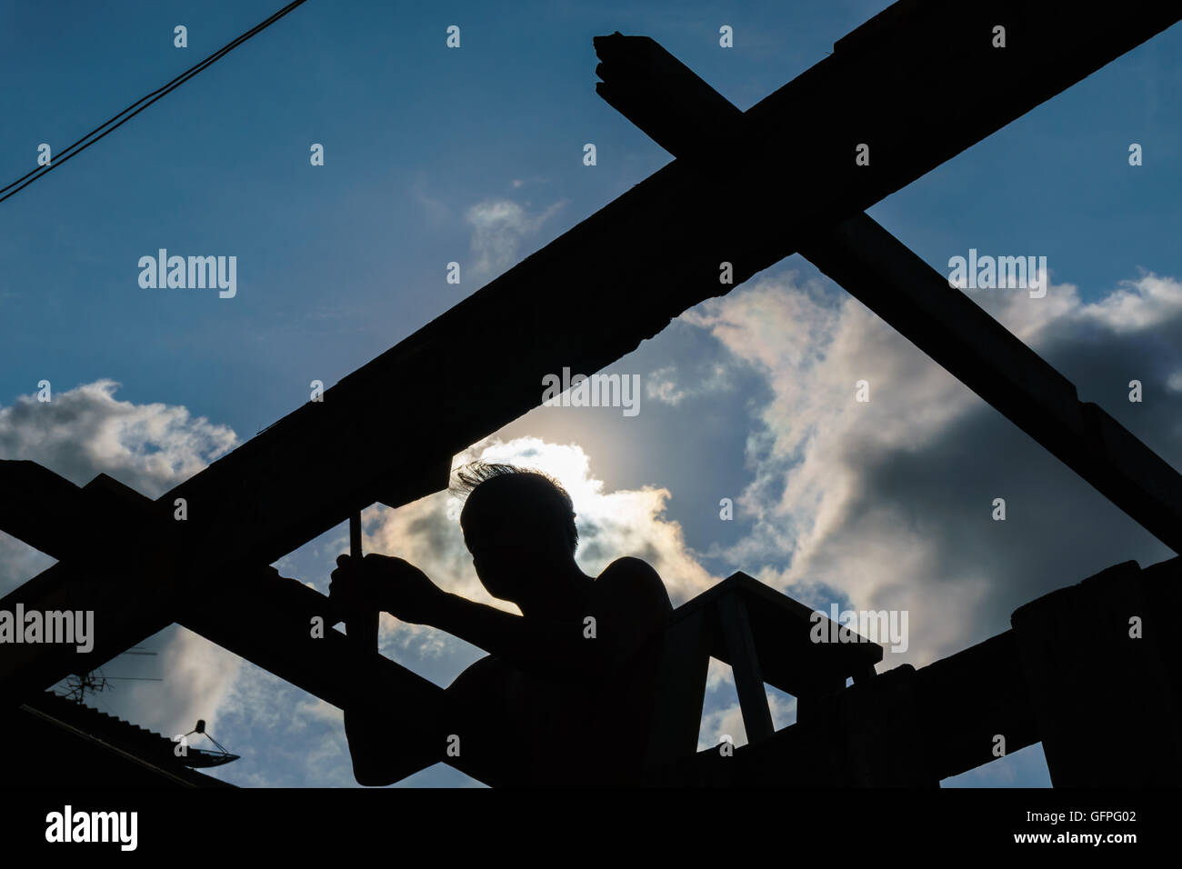 Carpenter working on top of the roof wooden structure, strong back ...