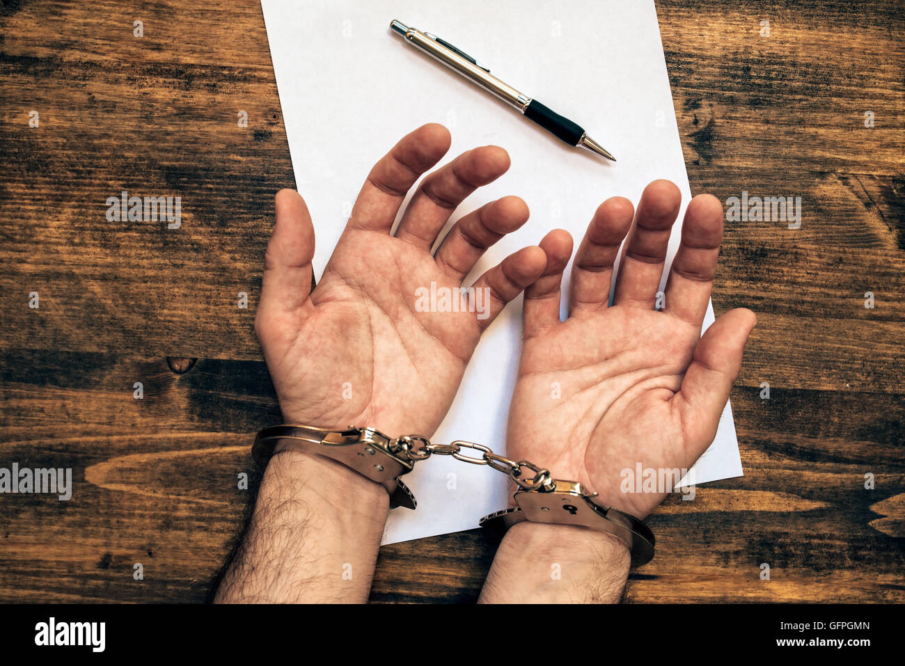 Male hands cuffed, top view of police investigator detective desk with ...