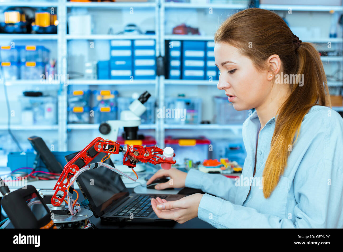 schoolgirl adjusts the robot arm model, girl in a robotics laboratory ...