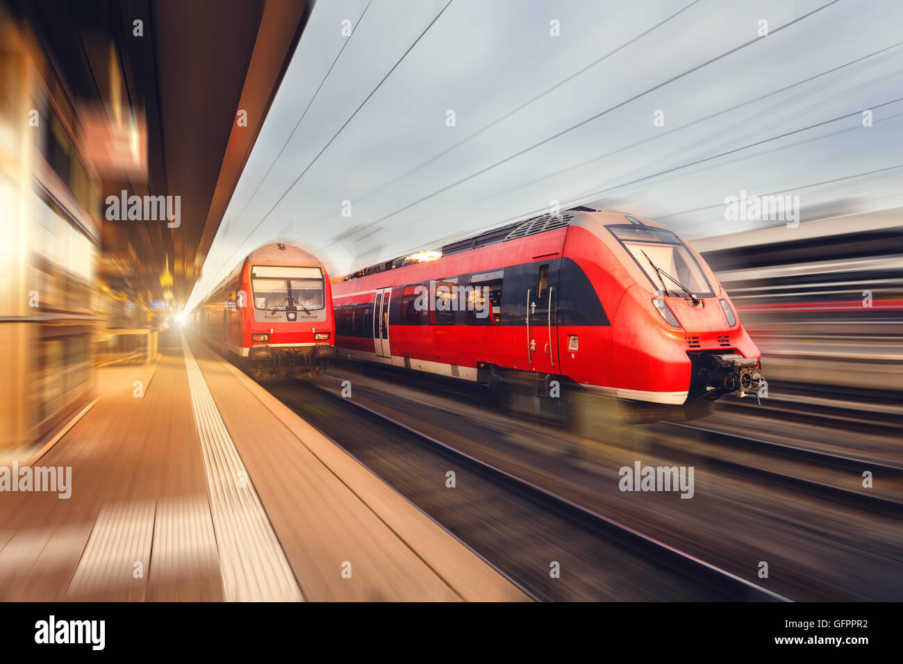 Modern high speed red passenger trains at sunset. Railway station in ...