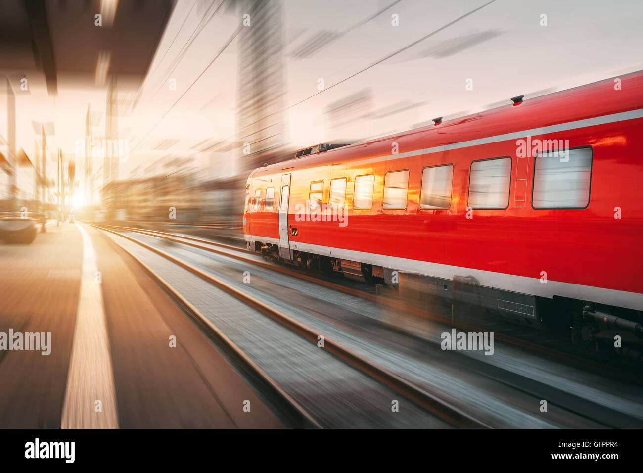 Modern high speed red passenger train moving through railway station in ...