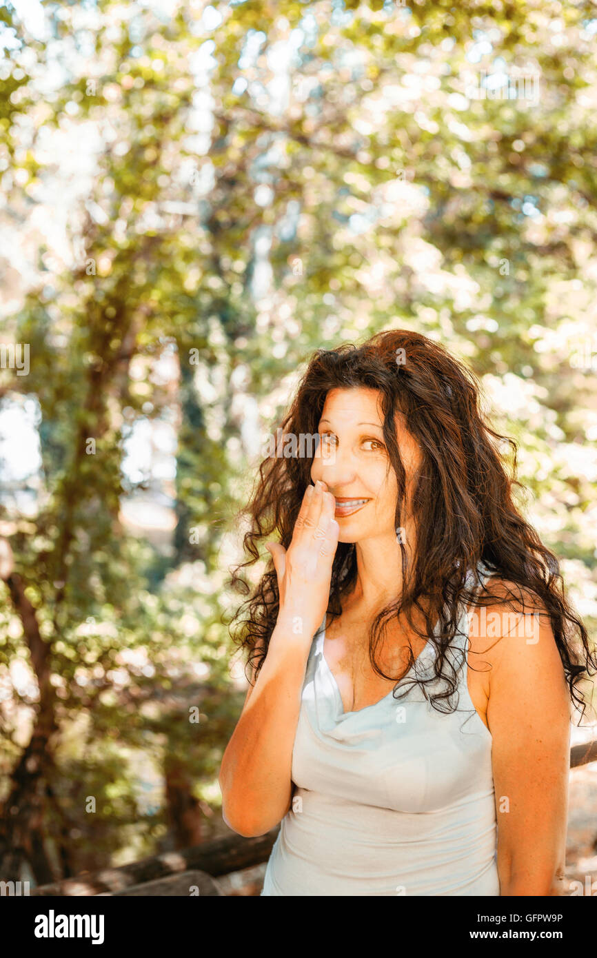Close Up Of Busty Classy Mature Woman Smiling At The Camera While Covering Her Mouth With Hand