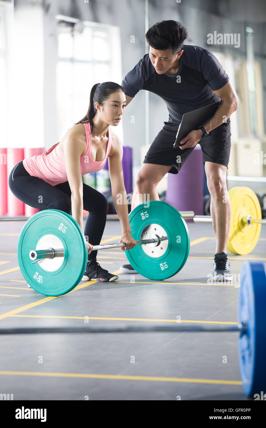 Young Chinese woman working with trainer at gym Stock Photo - Alamy