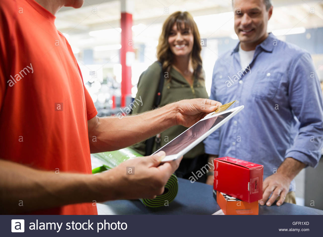 Couple paying using digital tablet credit card reader in home gym ...