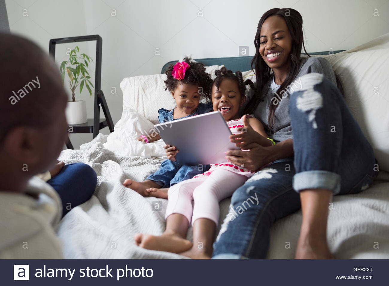 Young family using digital tablet on bed Stock Photo - Alamy