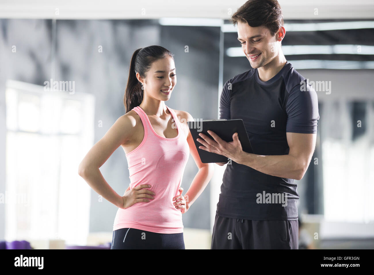 Young Chinese woman talking with trainer at gym Stock Photo - Alamy