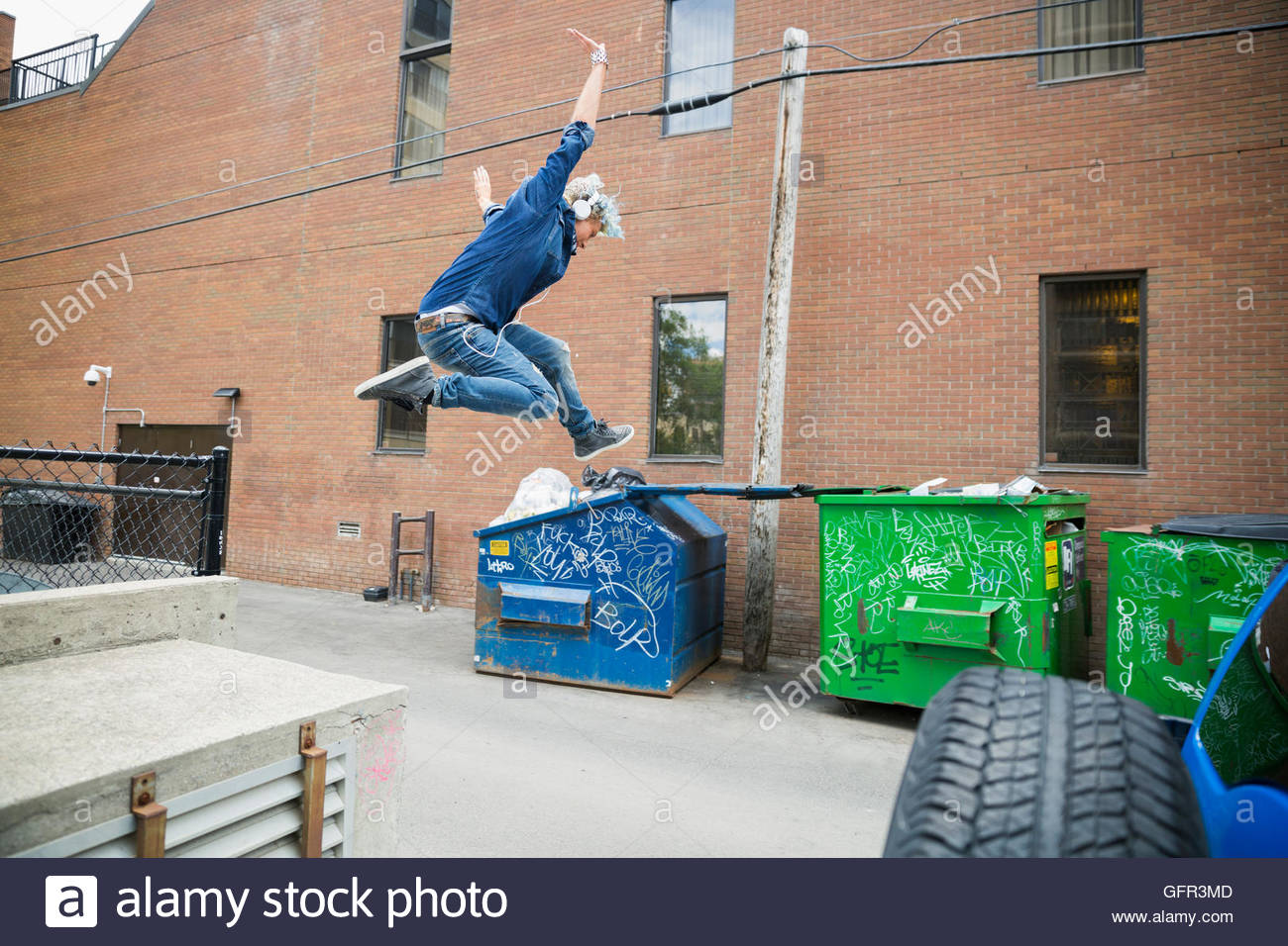 Cool young man jumping off ledge in urban alley Stock Photo - Alamy