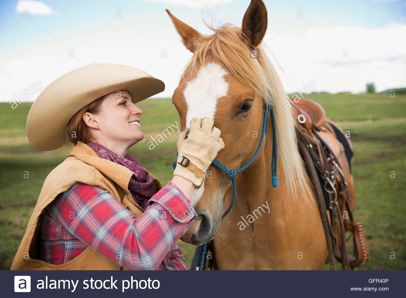 Smiling female cattle rancher petting horse Stock Photo - Alamy