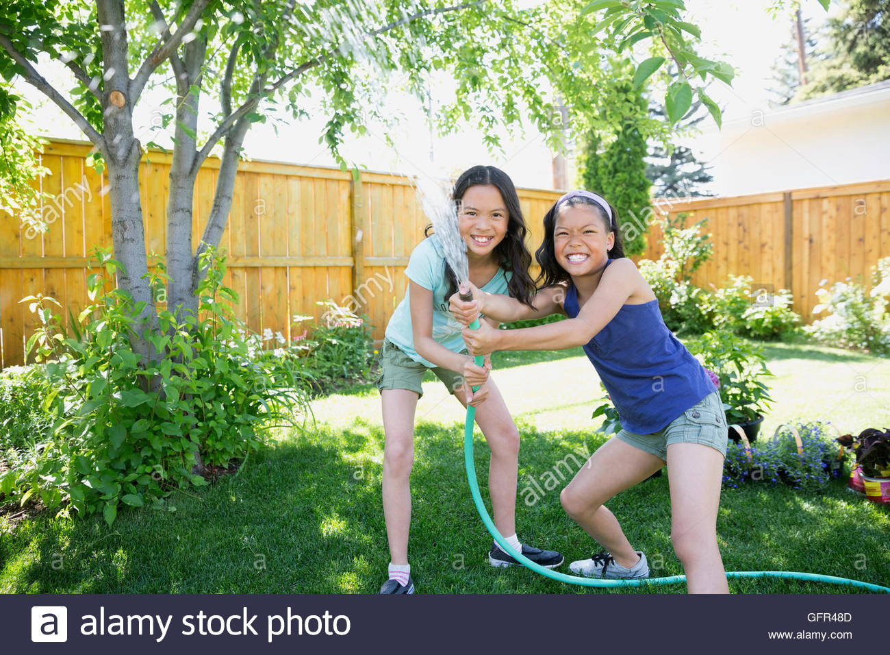 Portrait playful girls spraying hose in backyard Stock Photo - Alamy