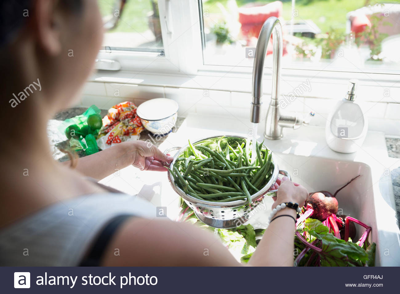 Woman washing green beans in colander at kitchen sink Stock Photo - Alamy