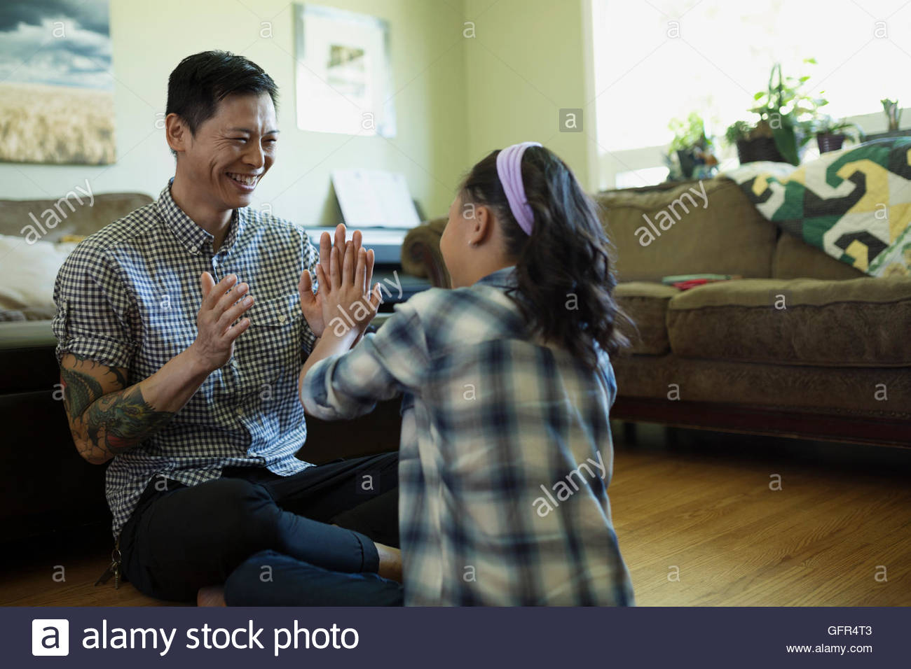 Father and daughter playing clapping game in living room Stock Photo ...