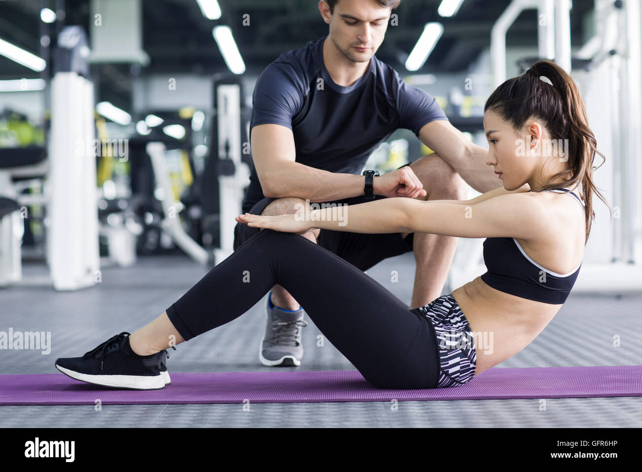 Young Chinese woman working with trainer at gym Stock Photo - Alamy