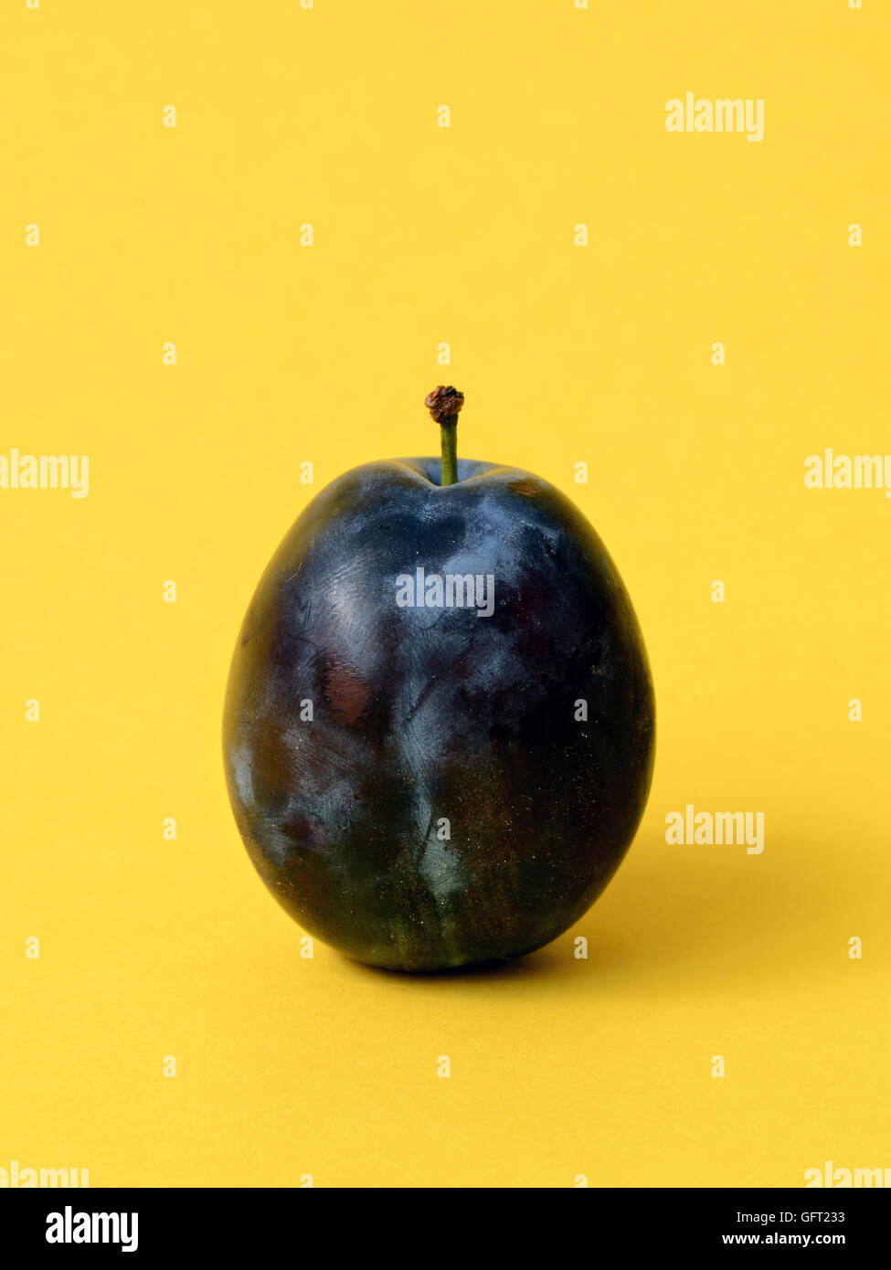 Single ripe prune, or plum on a yellow background Stock Photo - Alamy