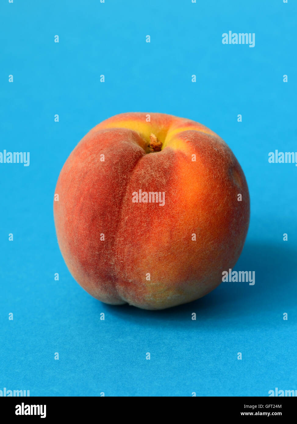 One ripe peach on a blue background Stock Photo - Alamy
