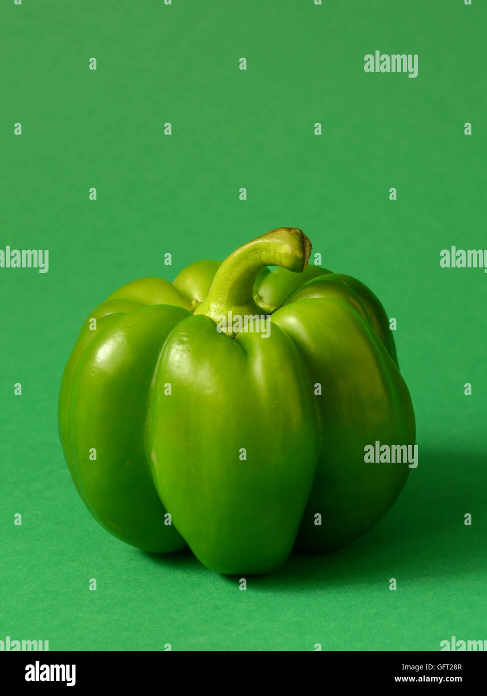 Green bell pepper on a green background Stock Photo - Alamy