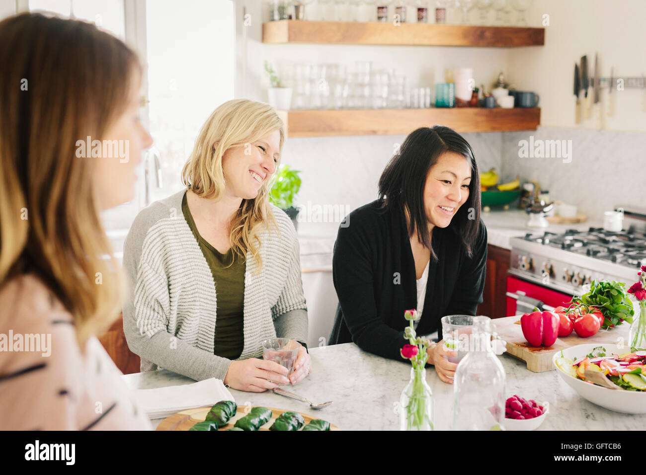 Three women in a kitchen preparing fresh food for lunch Stock Photo - Alamy