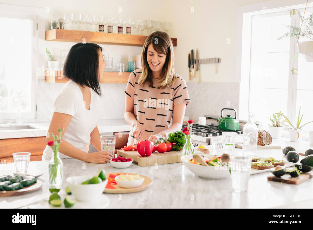 Two people women in a kitchen preparing lunch Stock Photo - Alamy