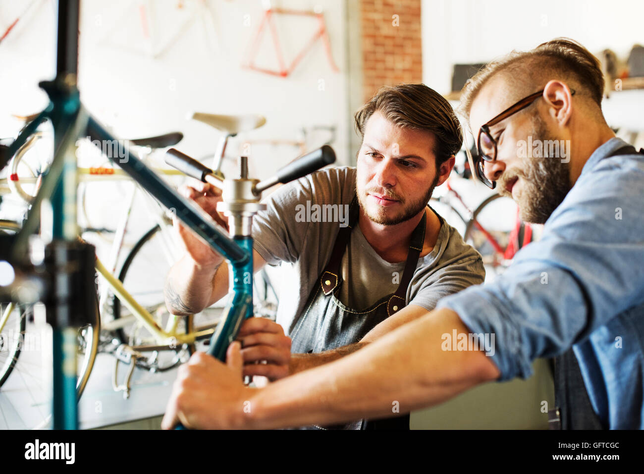 Two men in a cycle repair shop looking at a bicycle Stock Photo - Alamy