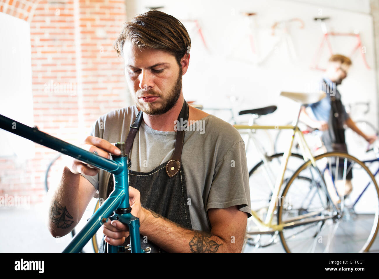 Two men in a cycle repair shop looking at a bicycle Stock Photo - Alamy