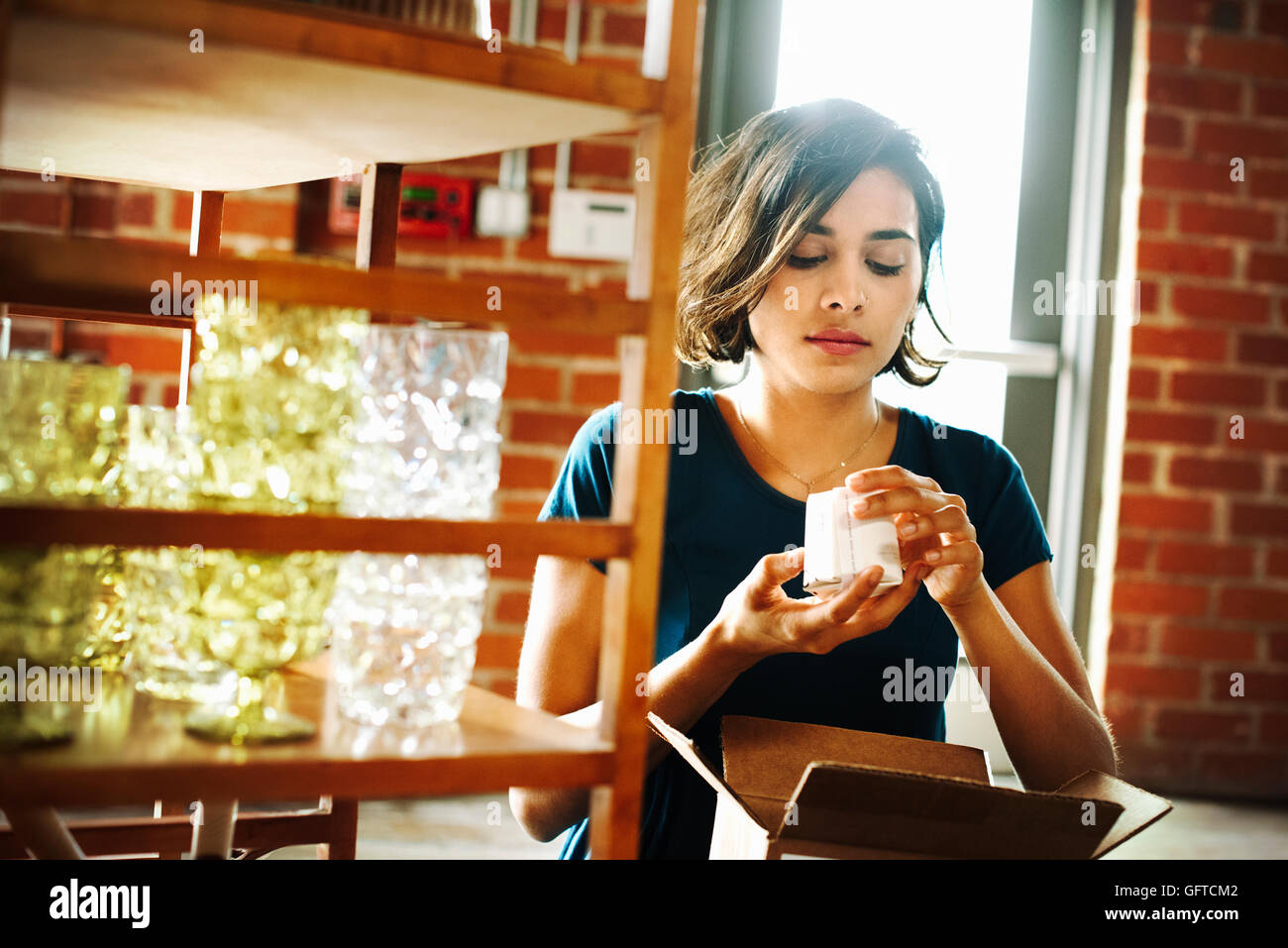 Young woman in a shop holding a small ceramic object Stock Photo - Alamy