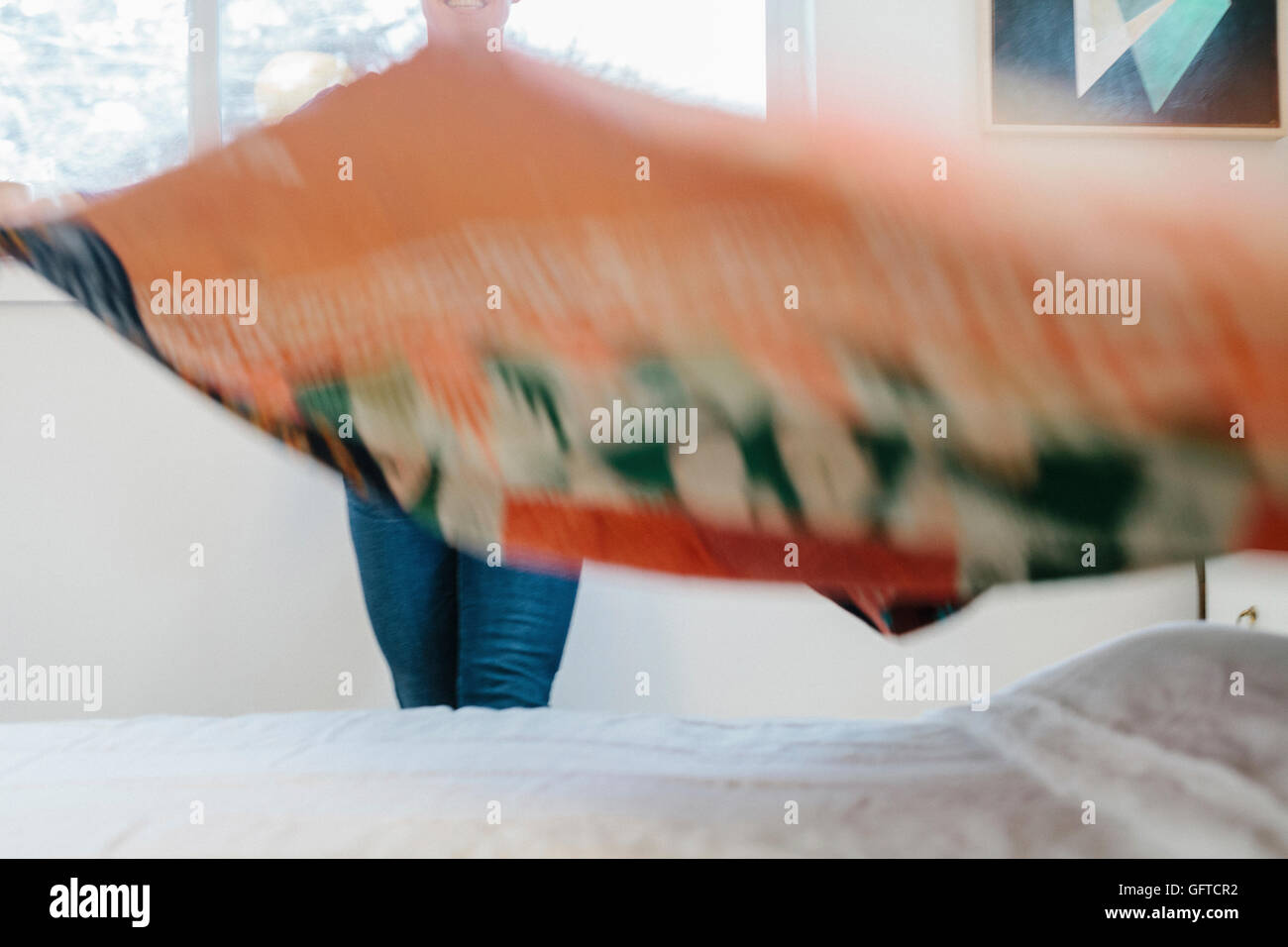 A woman throwing a quilt over a double bed Stock Photo - Alamy
