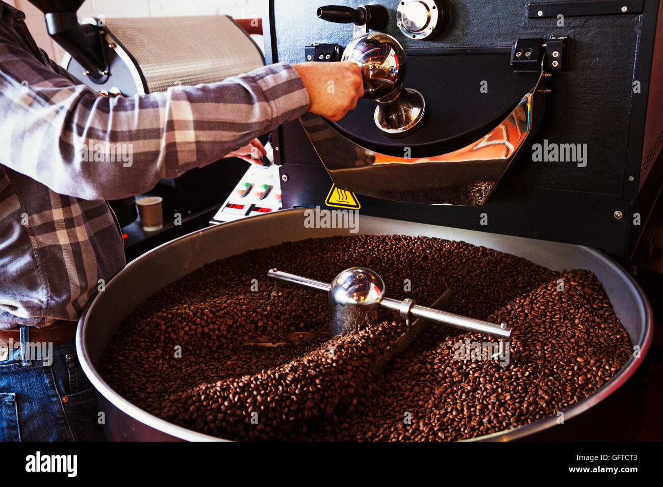 Coffee beans roasting in a drum being stirred with a metal paddle Stock ...