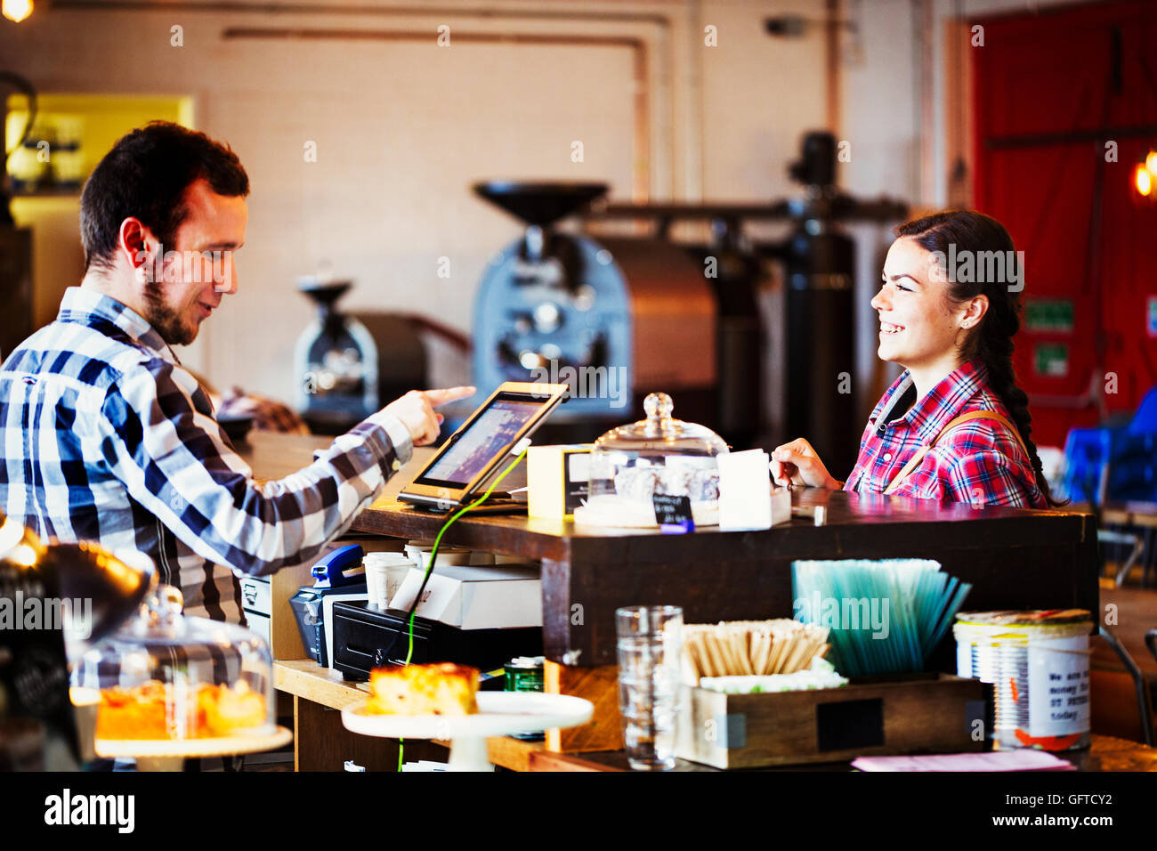 A man behind the counter using a touch screen to record transactions ...