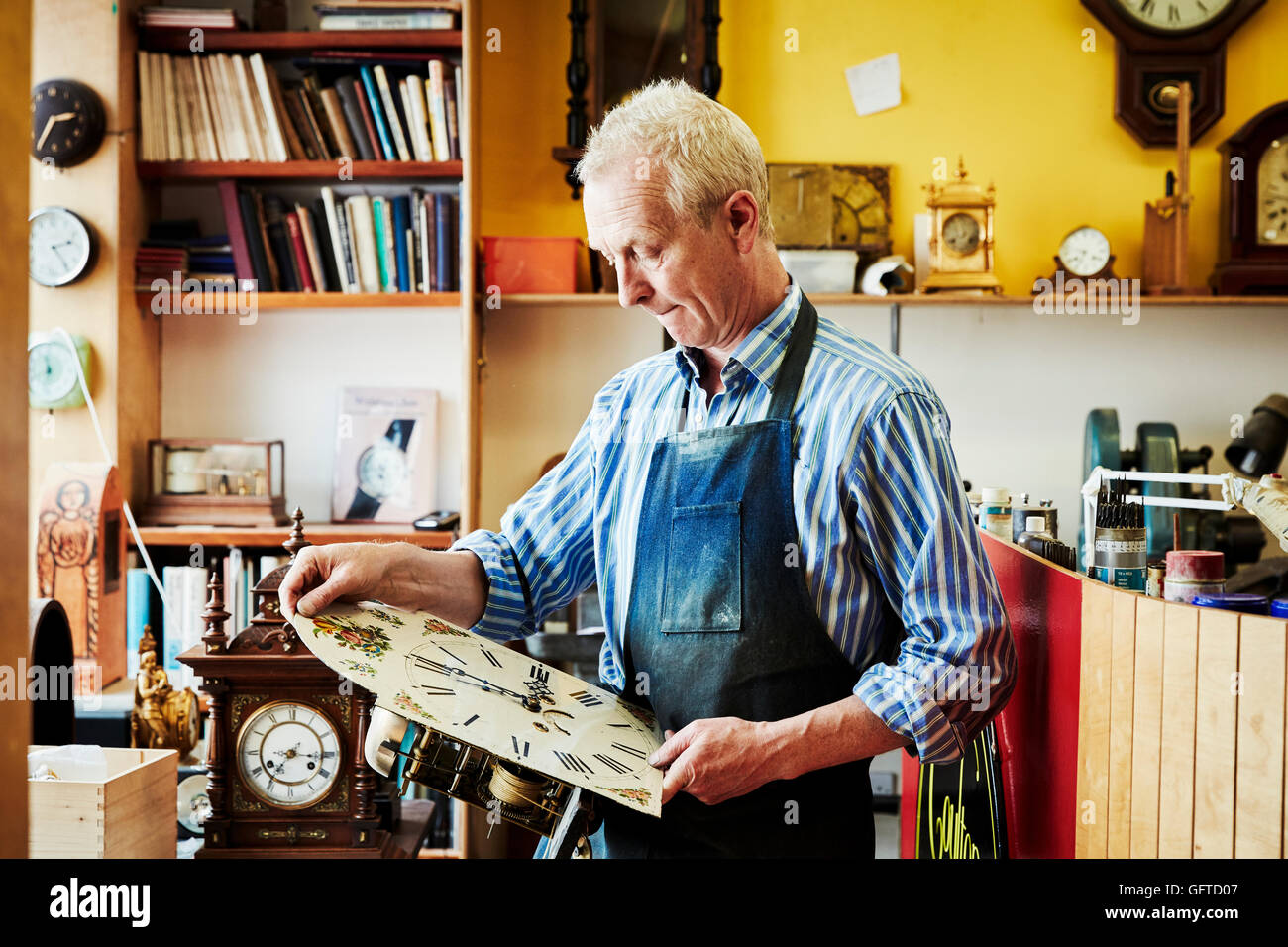 A clock maker viewing his work in the workshop Stock Photo - Alamy