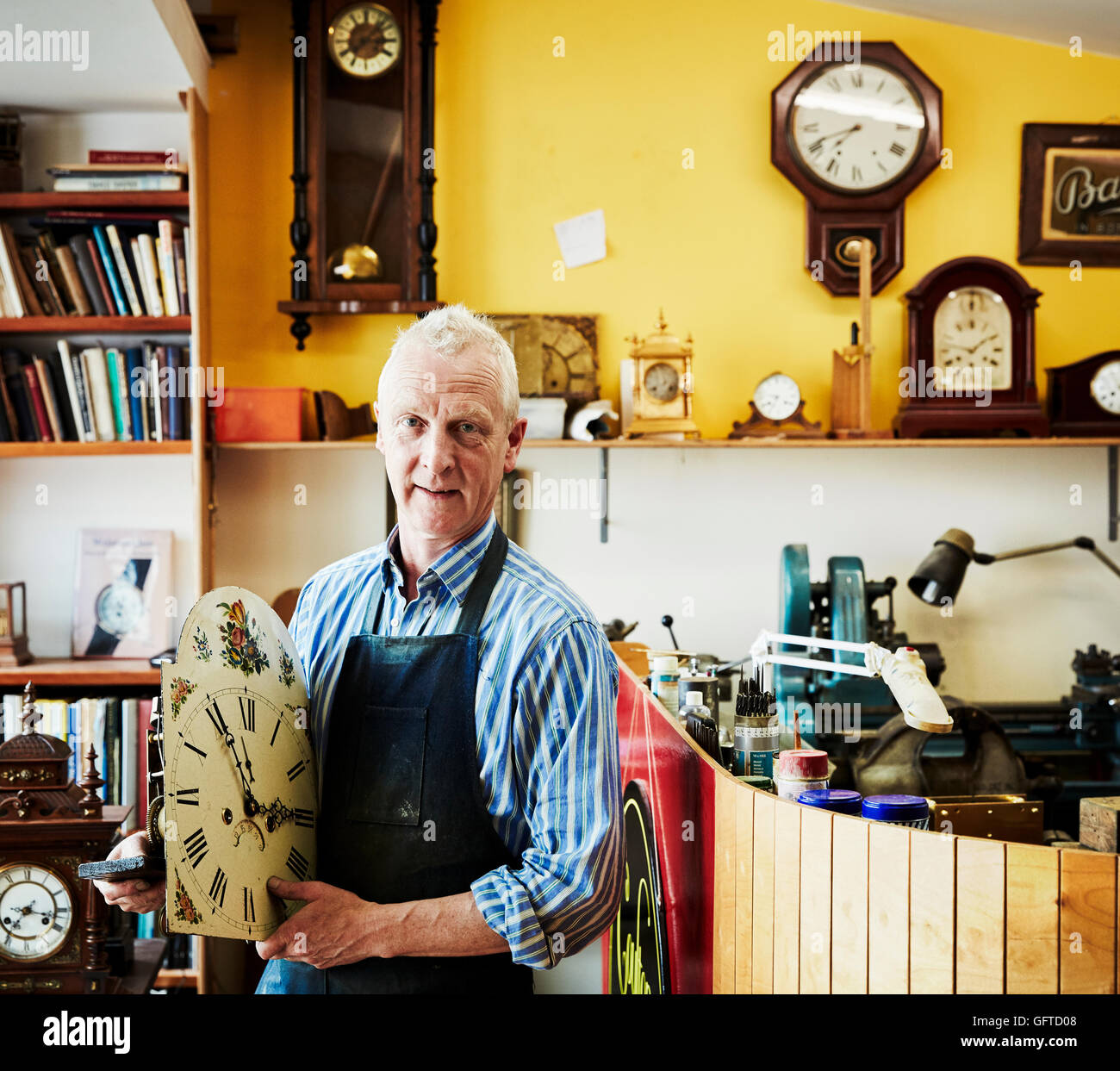A clock maker showing off his work in his workshop Stock Photo - Alamy