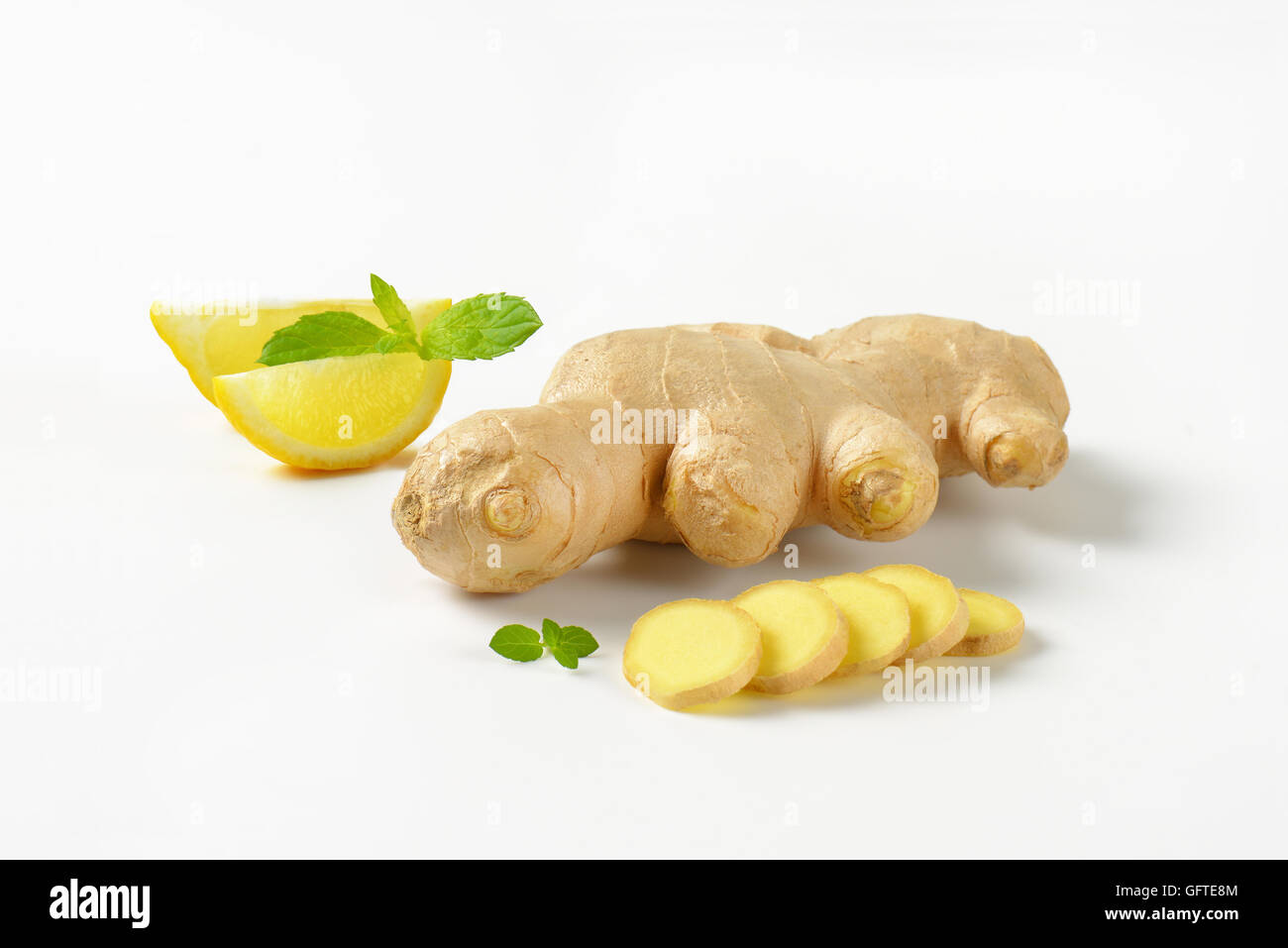 sliced ginger with lemon and mint on off-white background with shadows ...