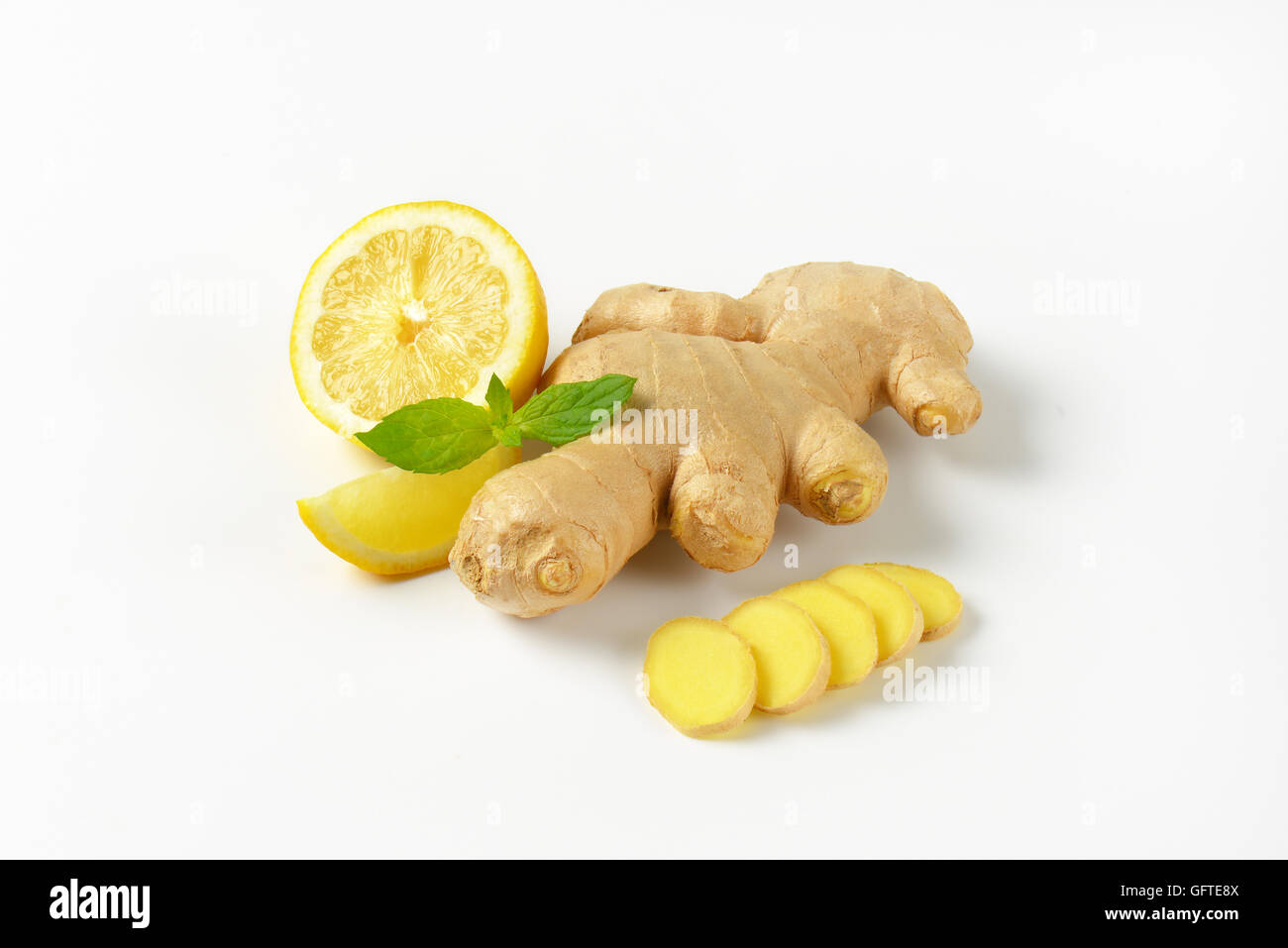 sliced ginger with lemon and mint on off-white background with shadows ...
