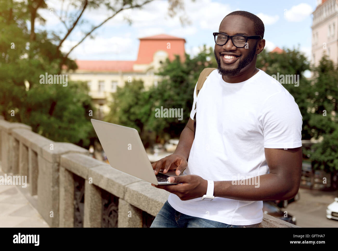 Positive smiling man using laptop Stock Photo - Alamy