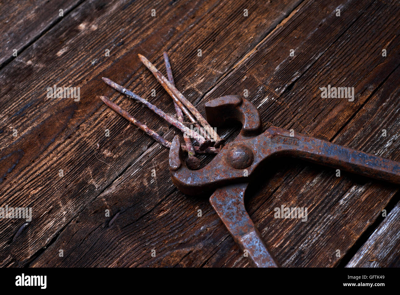 Old rusty tongs with nails on wooden boards background Stock Photo - Alamy
