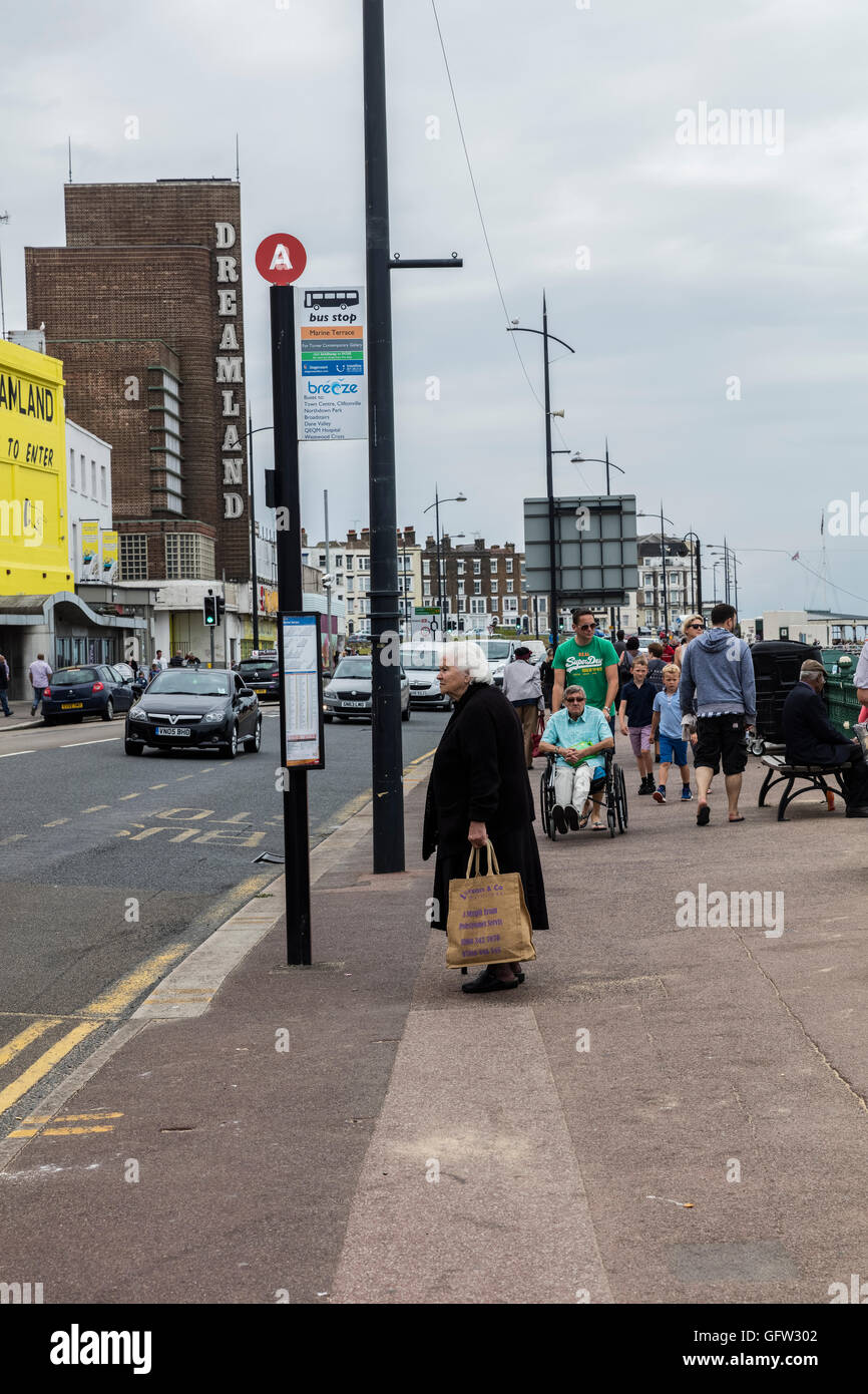 Elderly lady dressed in black waits at a bus stop in Margate on the ...