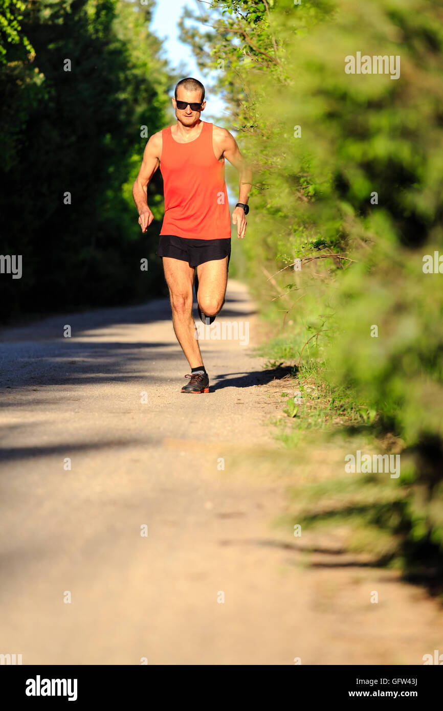 Man runner running on country road in summer sunset. Young athlete male ...