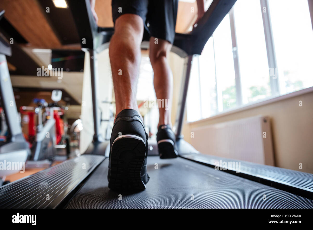 Back view of young sportsman in black sneakers running on treadmill in ...
