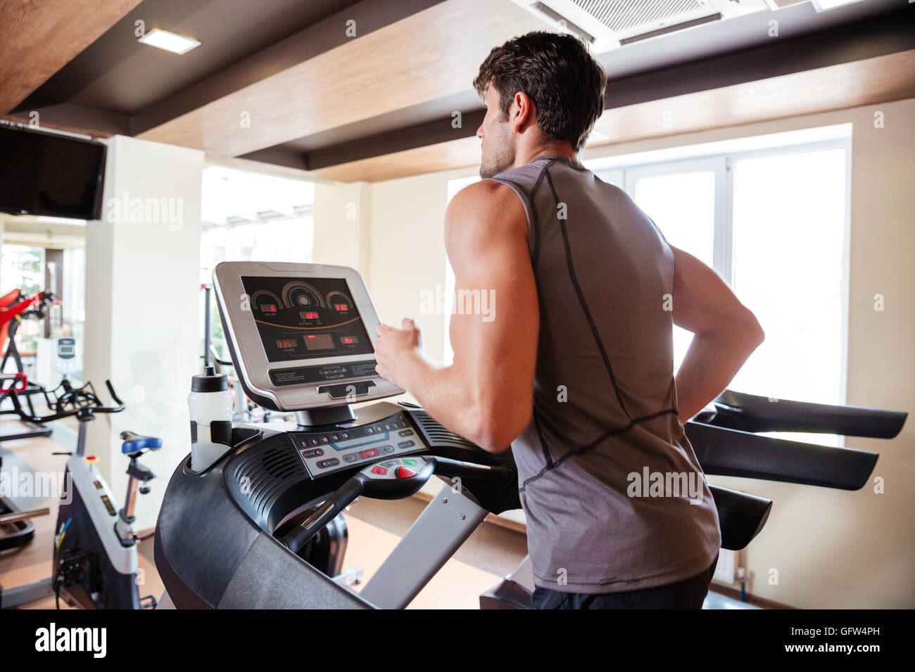 Back view of young sportsman working out and running on treadmill in ...
