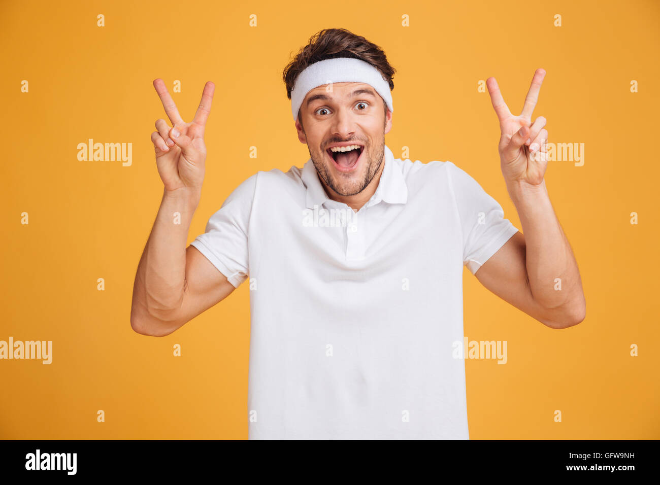 Happy excited young male athlete shouting and showing victory sign with ...