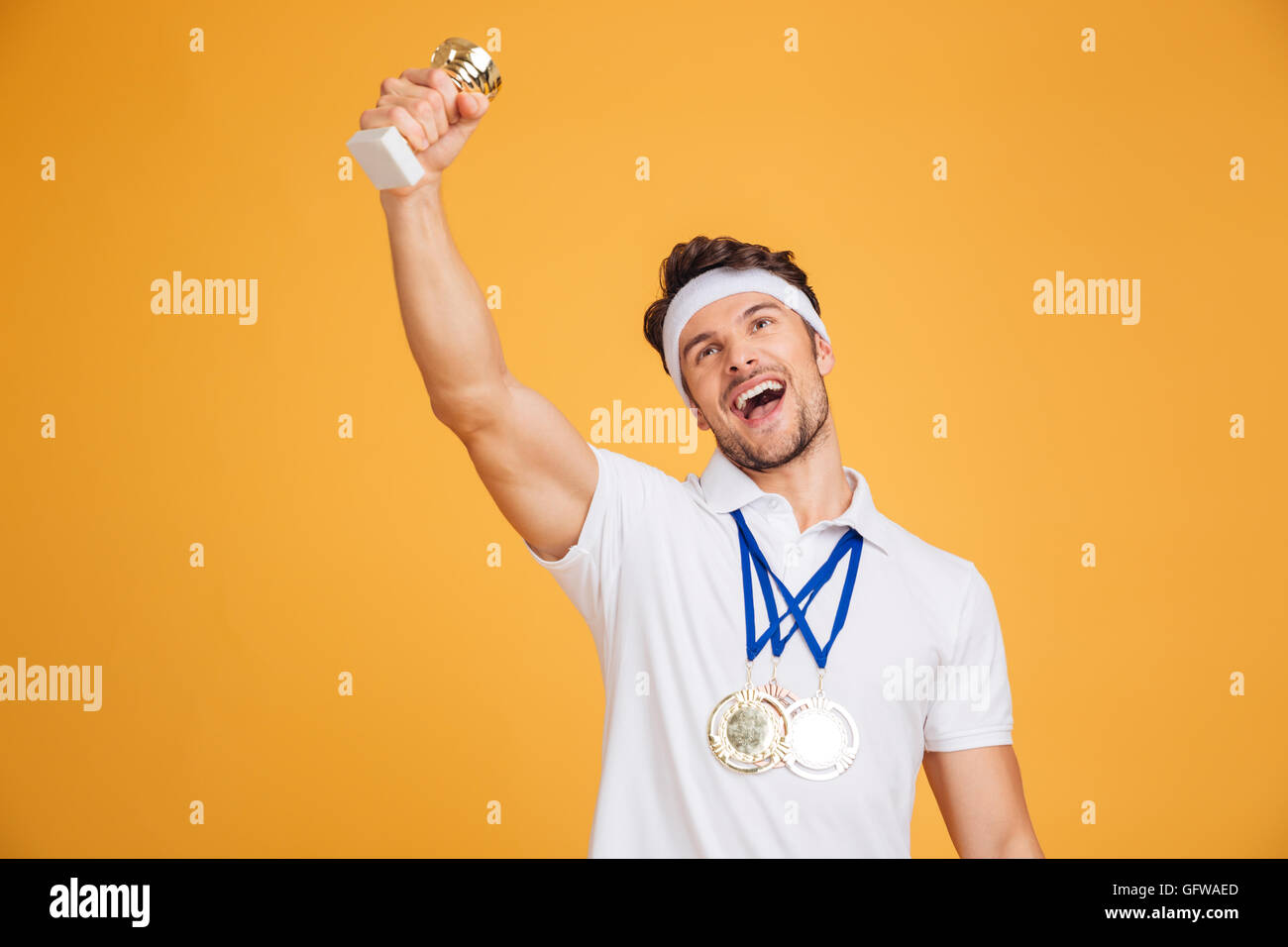 Happy young man athlete with three medals and trophy cup celebrating ...